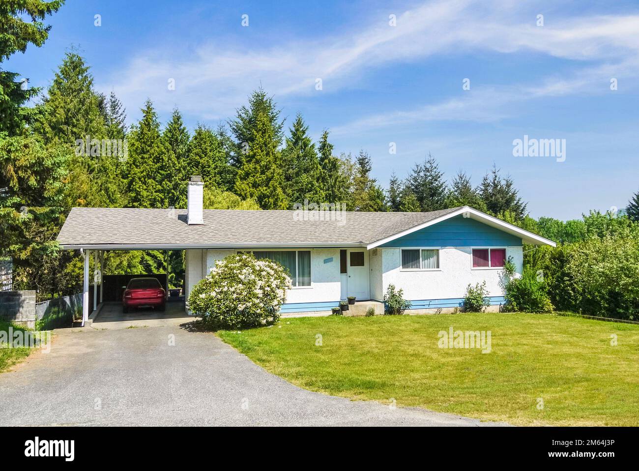 Modest residential house with big front yard and a car parked under ...