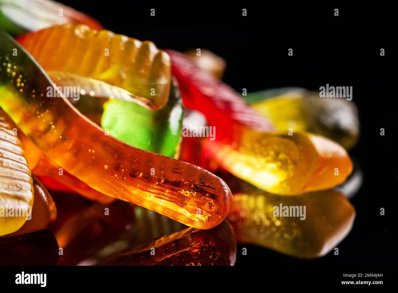 Juicy colorful jelly worms sweets. Gummy candies. Snakes. On black ...