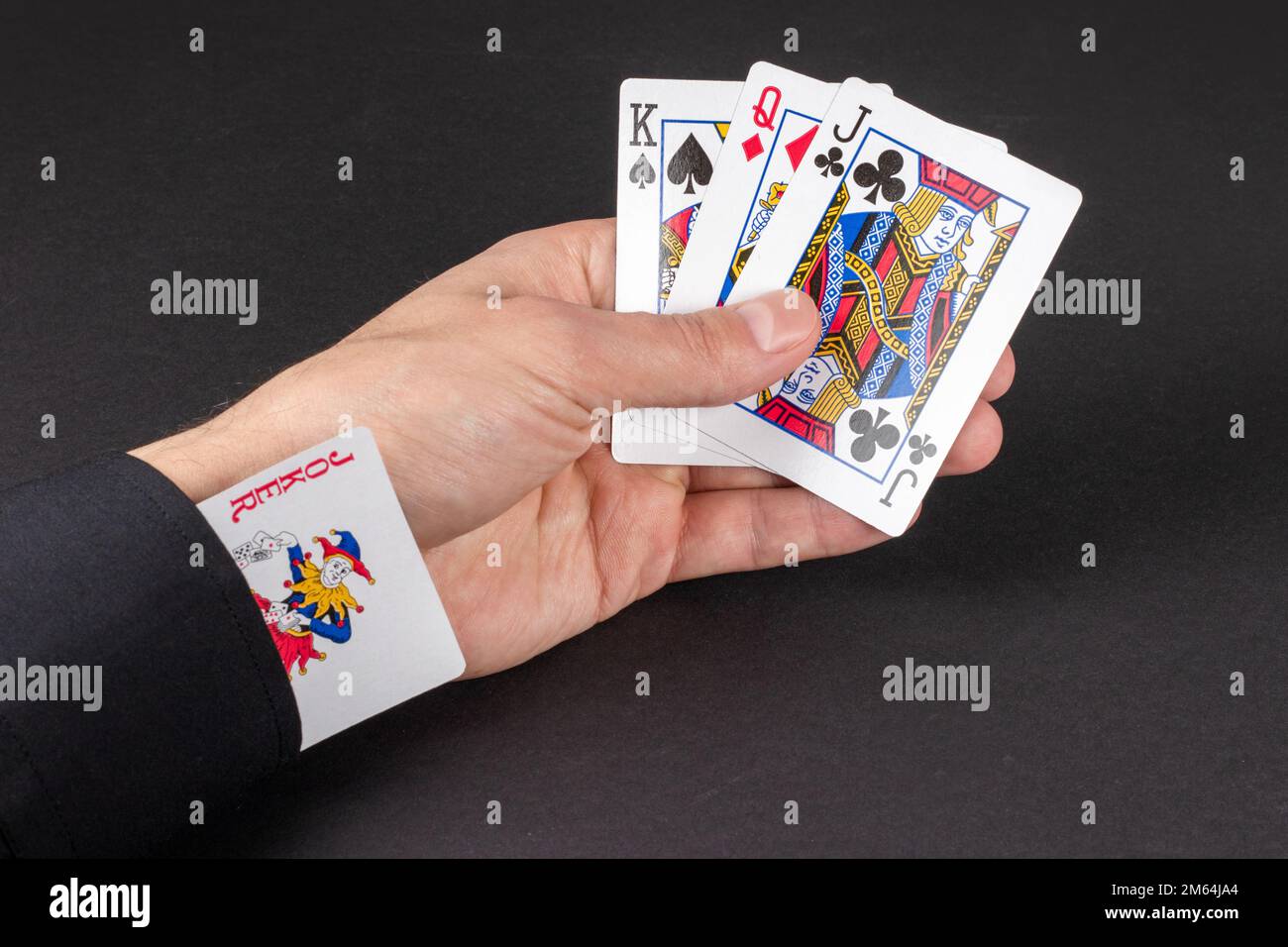Concept - joker card in the sleeve. A man holding cards in his hands on ...