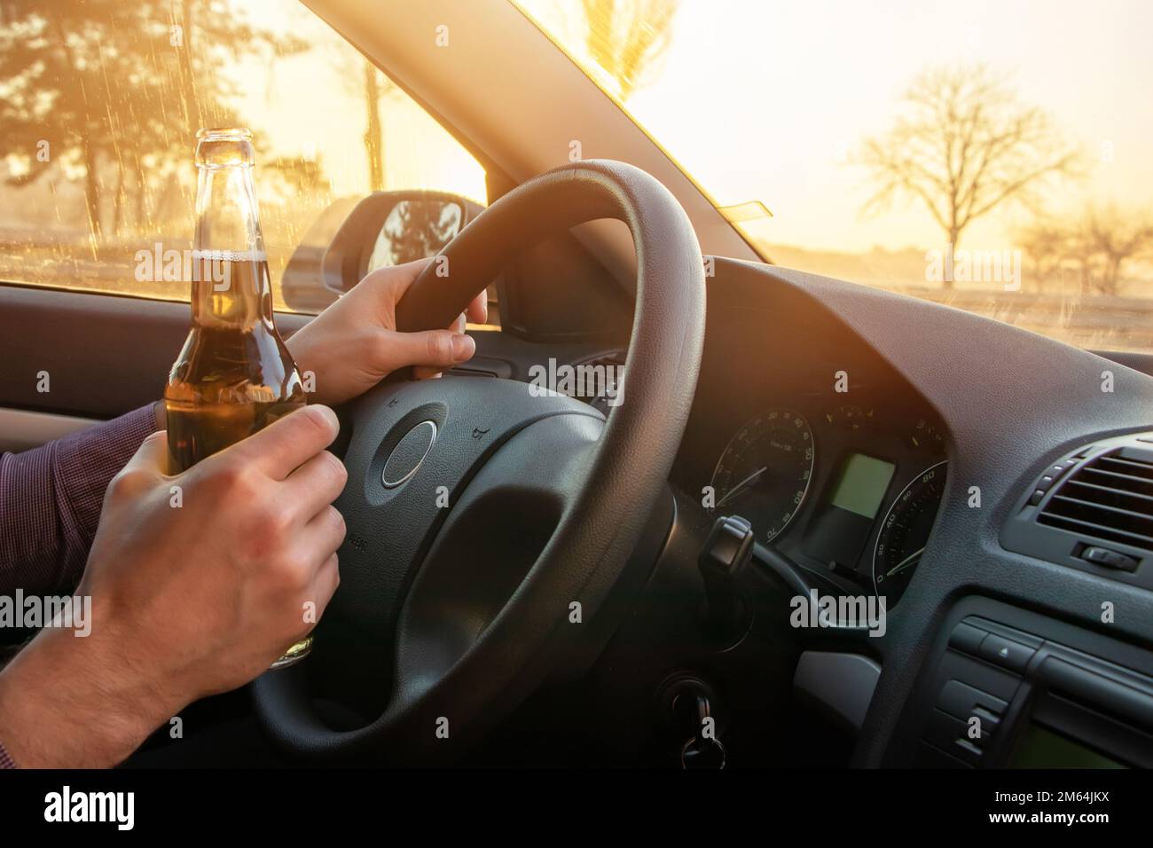 Man drinking alcohol while driving in his car on sunset Stock Photo - Alamy
