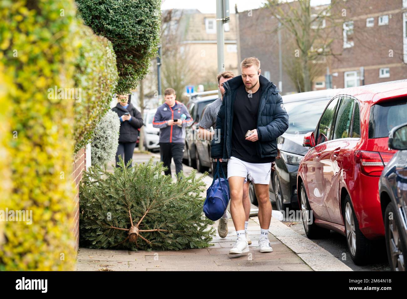 People walk around a Christmas tree discarded on the pavement in Balham ...