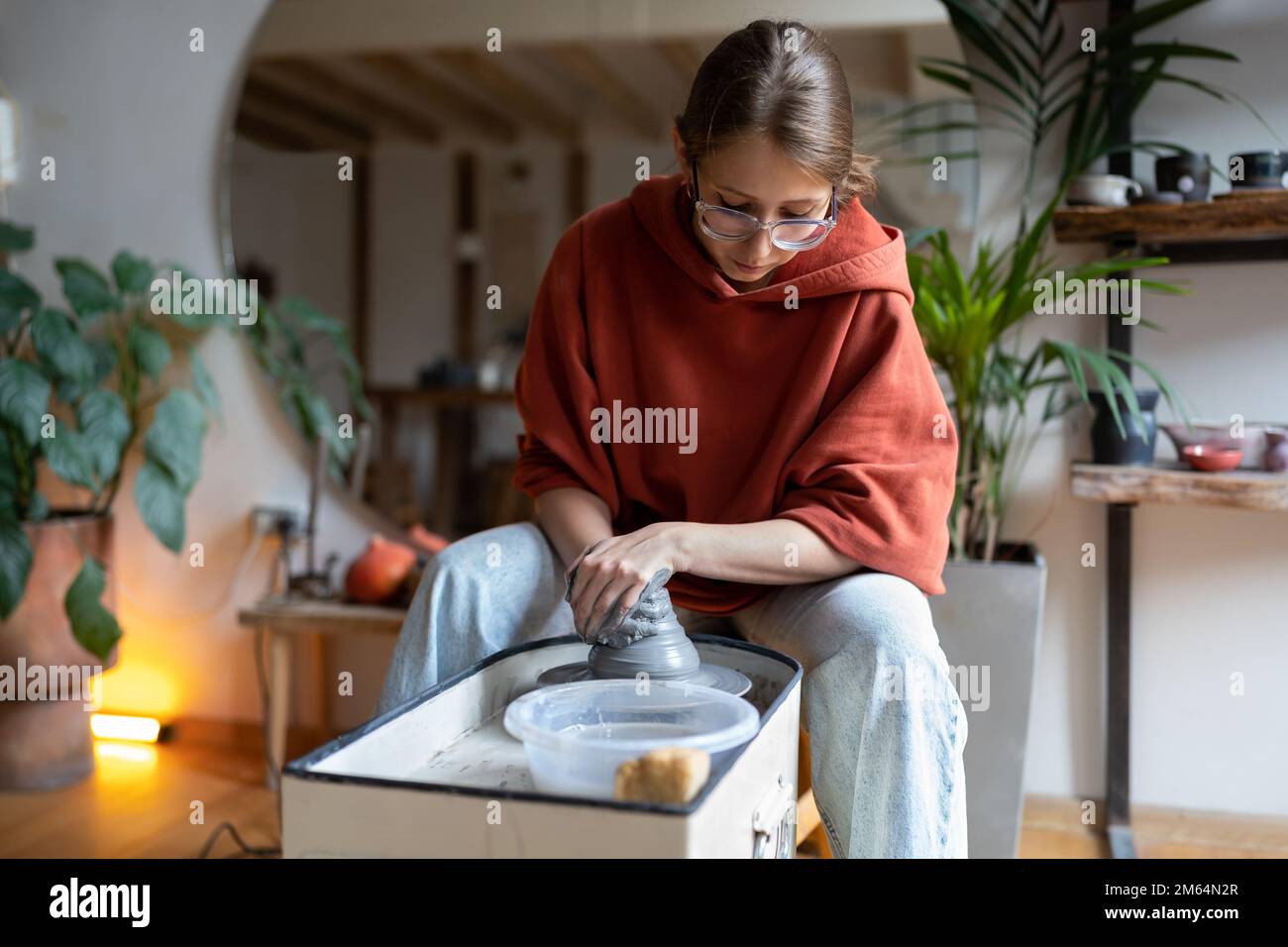 Young focused woman local ceramic artist working with clay on wheel in ...