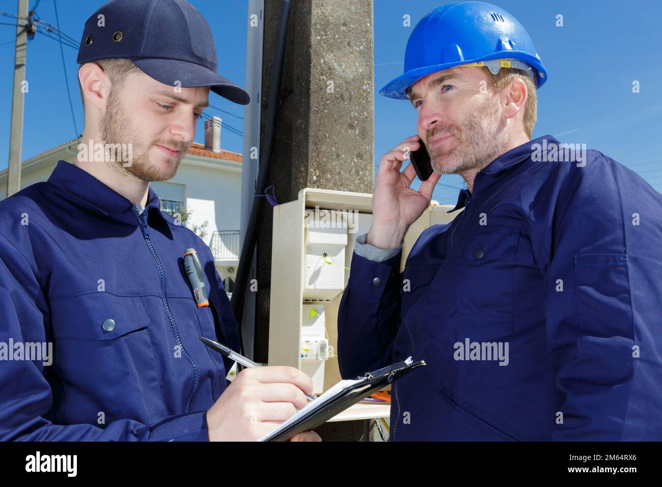 workers next to transmission line tower Stock Photo - Alamy