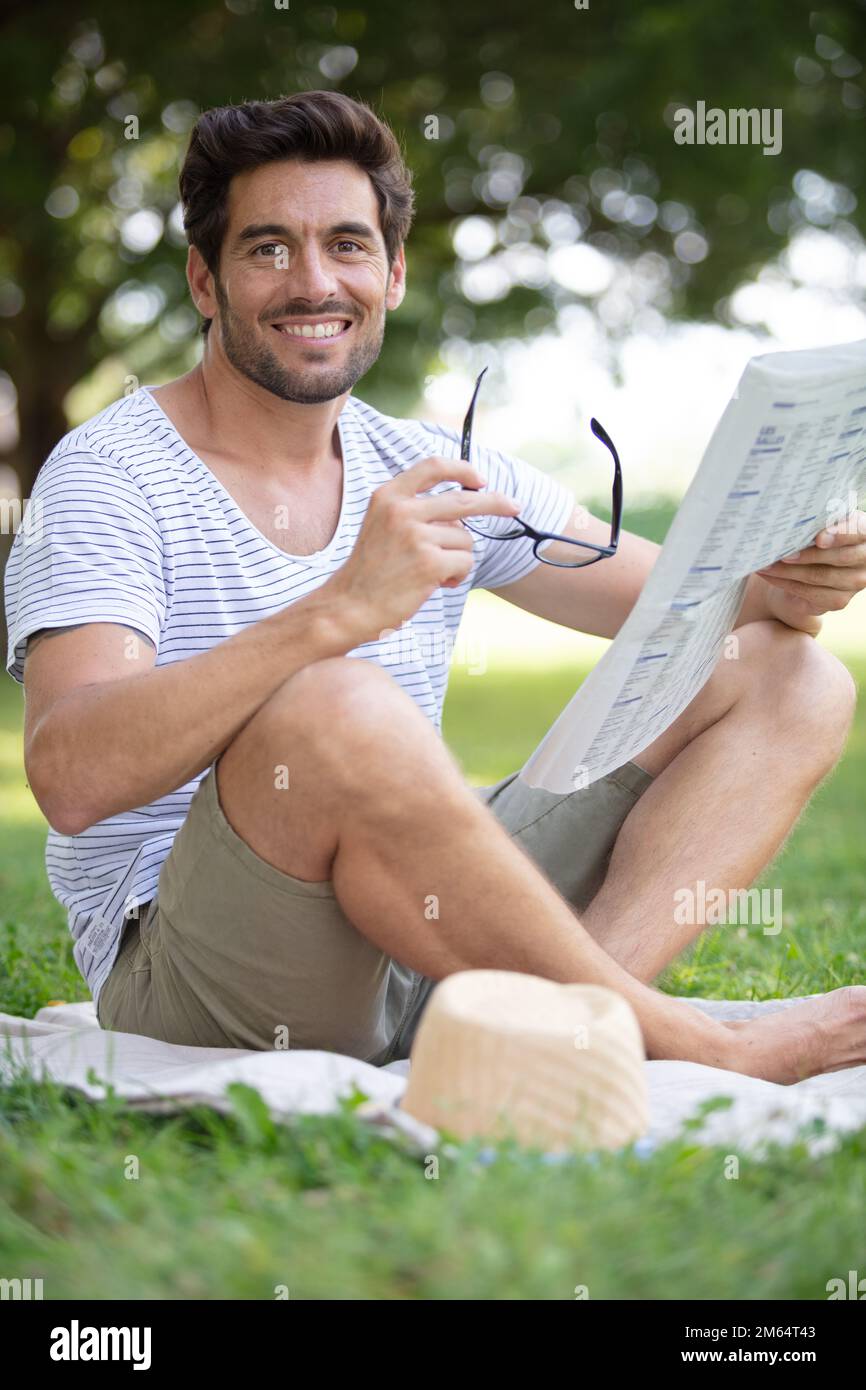 casually dressed man sat on the grass reading a newspaper Stock Photo ...
