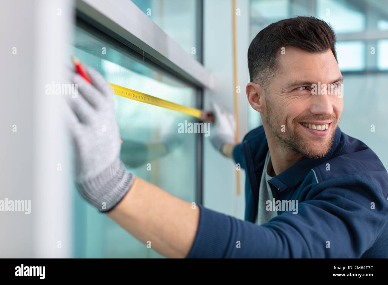 man using spirit level on window and looking over shoulder Stock Photo ...