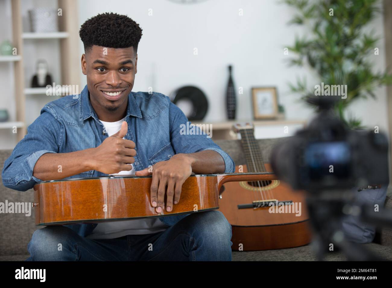 man recording a guitar tutorial holding thumbs up Stock Photo - Alamy