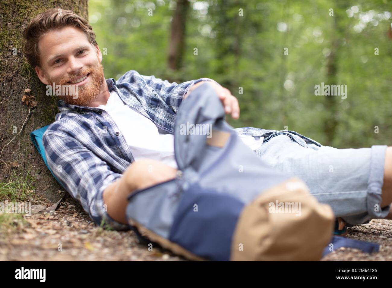 Man sitting against tree trunk hi-res stock photography and images - Alamy