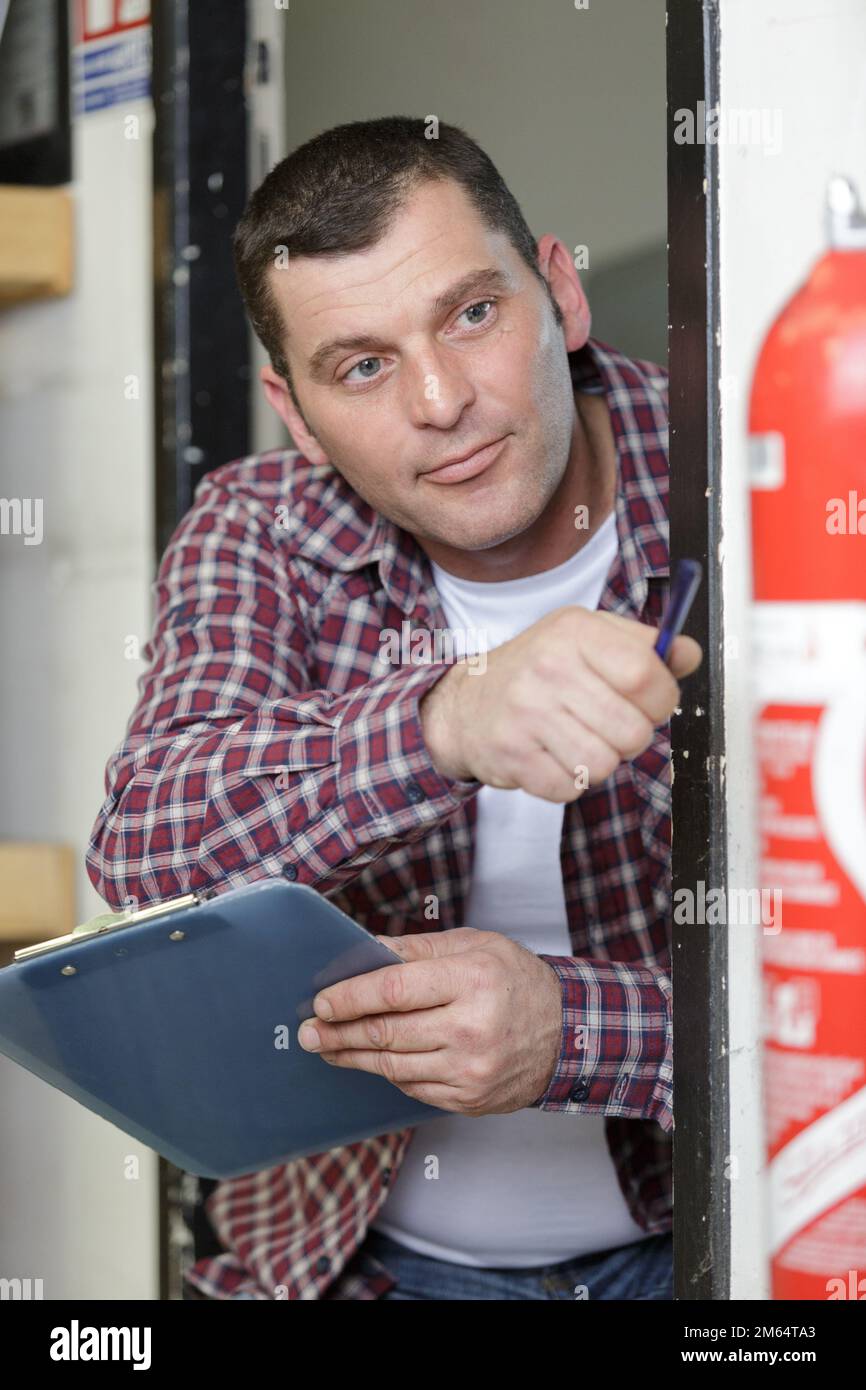 man checking fire extinguisher writing on document Stock Photo - Alamy