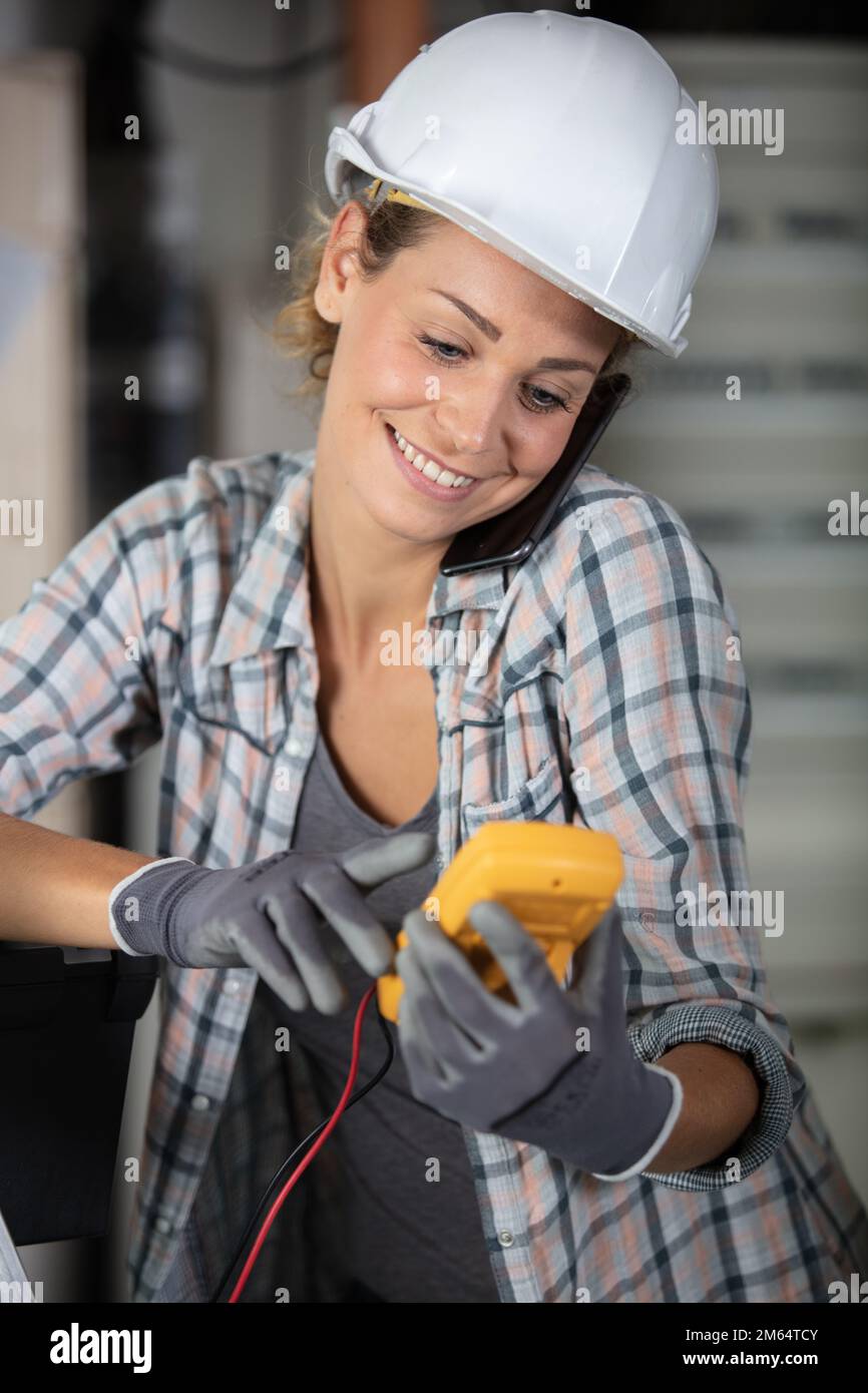 female electrician using multimeter while talking on telephone Stock ...
