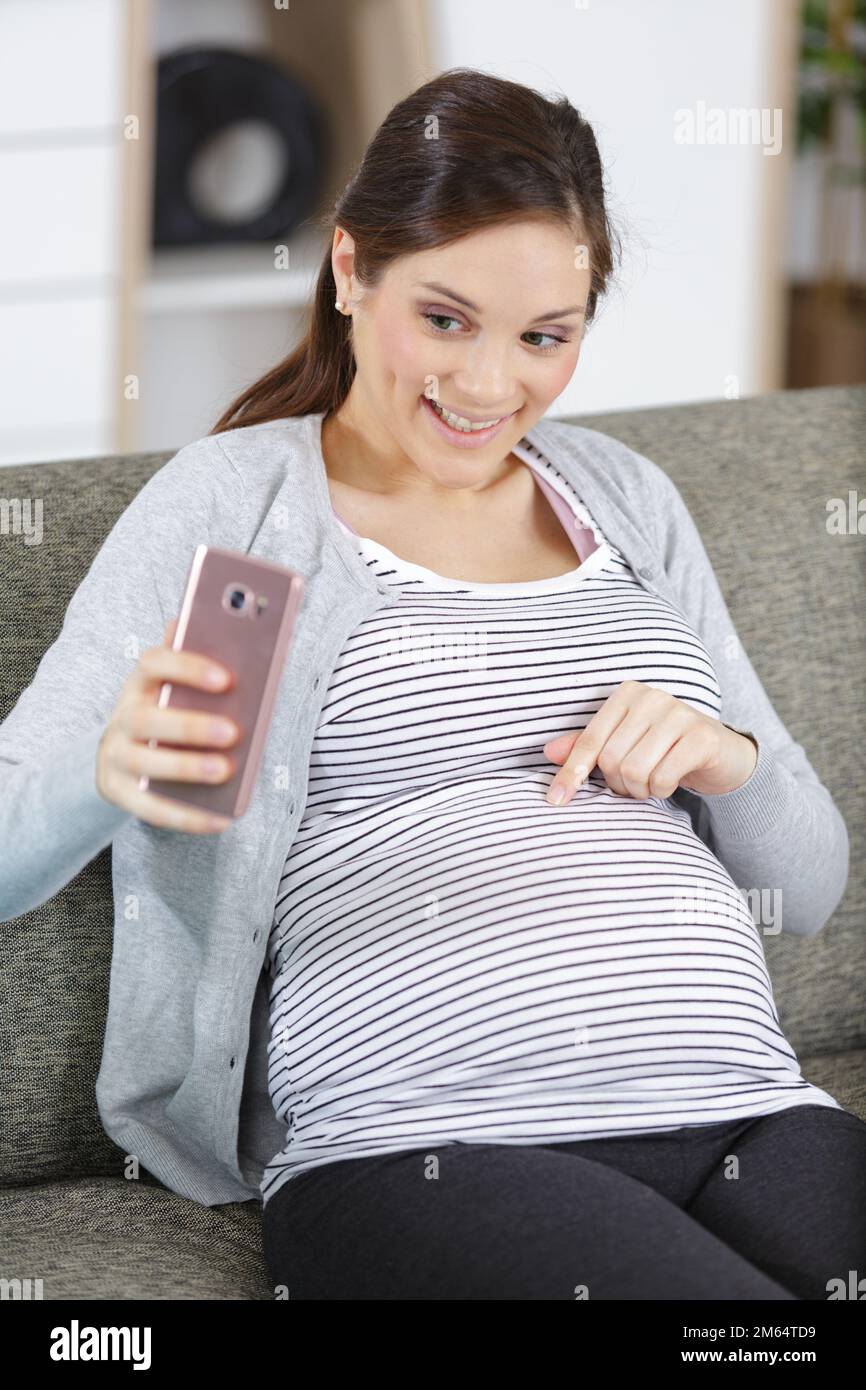 pregnant lady showing her bump on a smartphone chat Stock Photo - Alamy