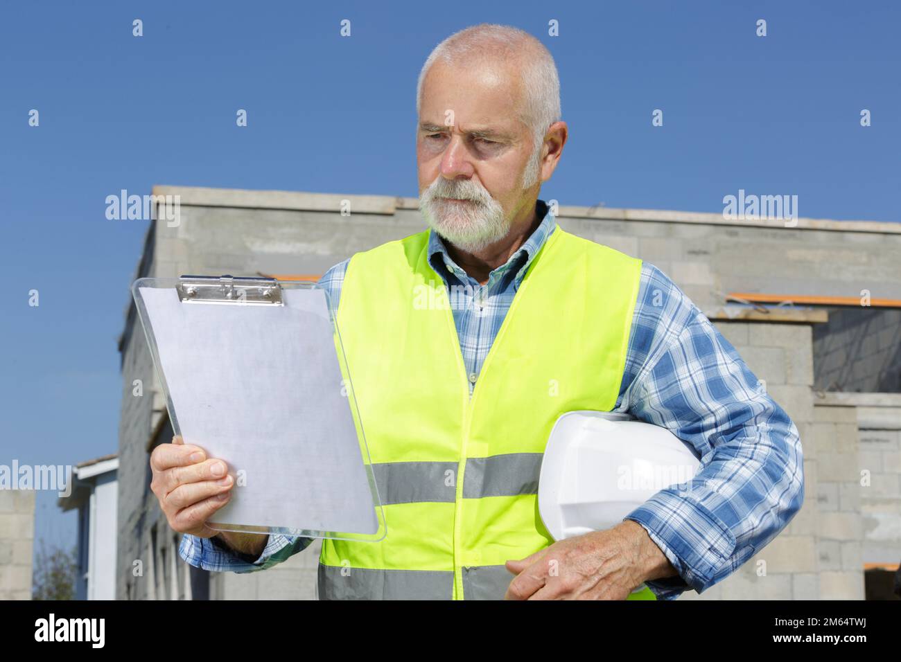 male civil engineer wearing protective vest and hardhat checking ...
