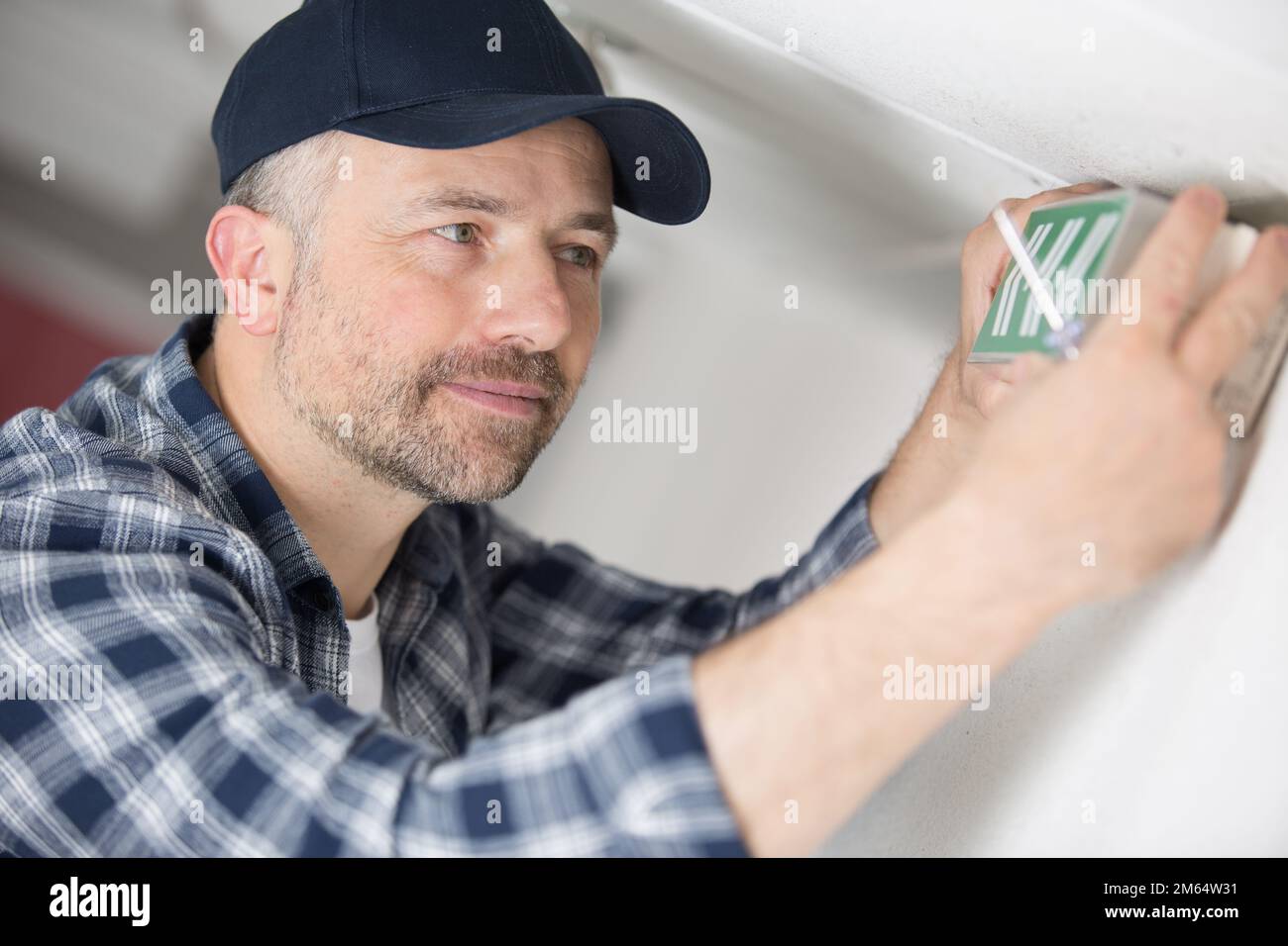 technician placing an emergency exit sign Stock Photo - Alamy