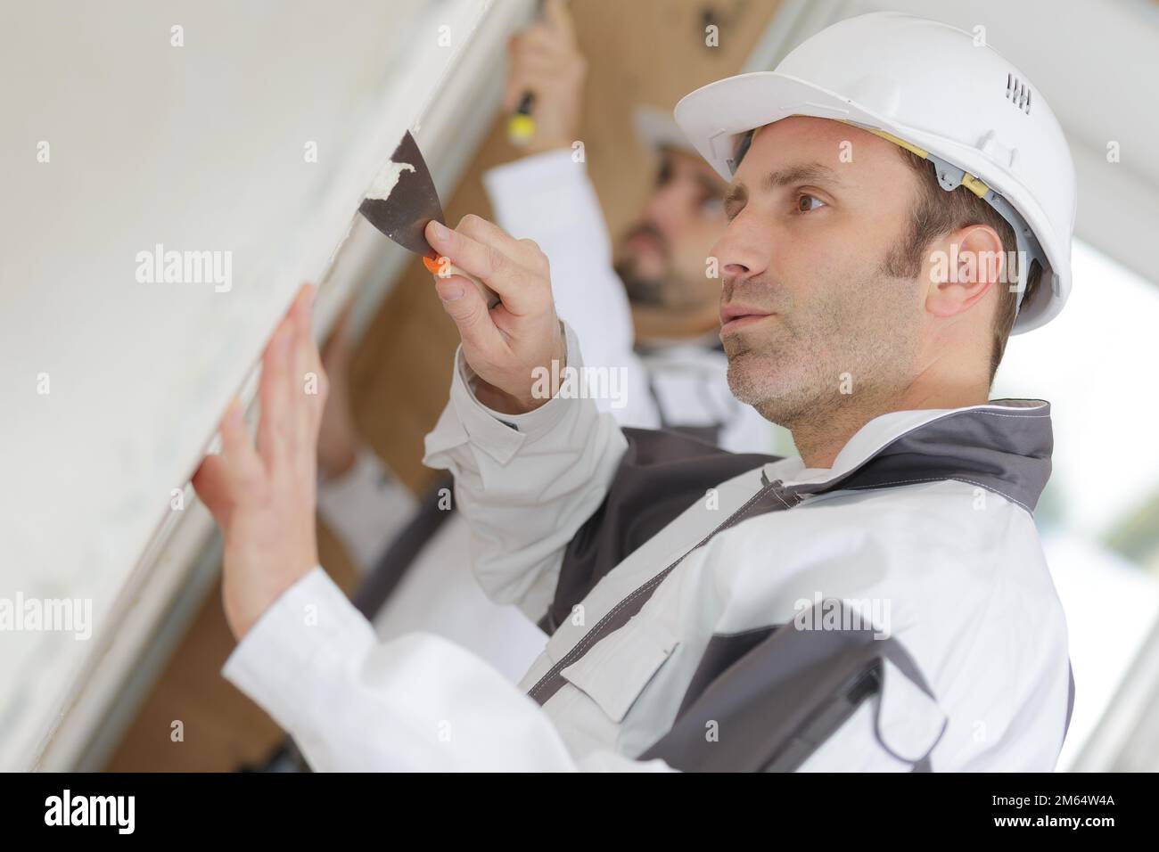 Contractor removing wallpaper with a scraper Stock Photo - Alamy