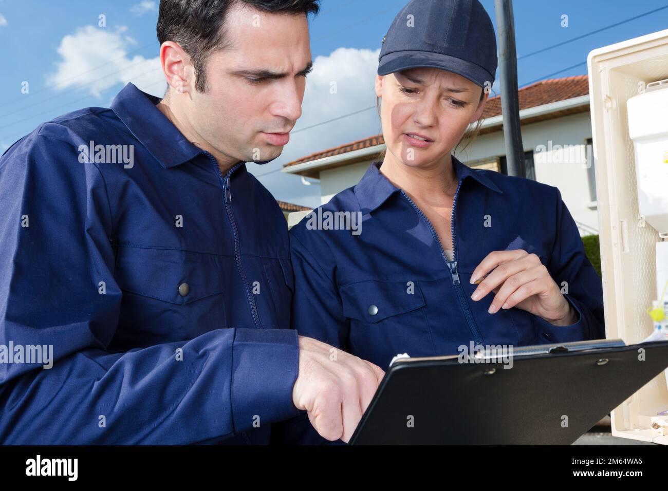 two male electricians looking at connection in outdoor Stock Photo - Alamy