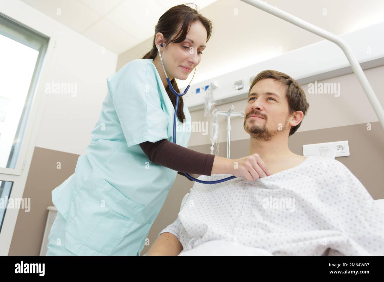 doctor checking heart beat of patient in bed Stock Photo - Alamy
