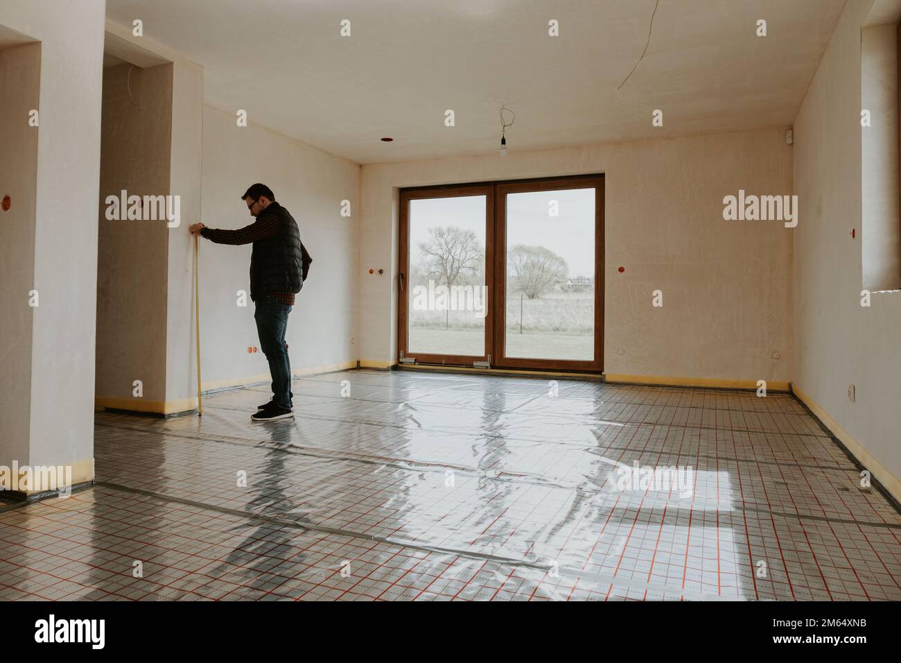 Builder measuring wall with tape Stock Photo - Alamy