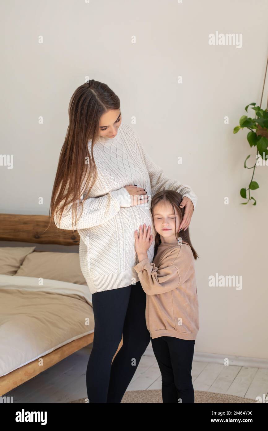 Cute little girl listening to baby's moves in pregnant moms belly Stock ...