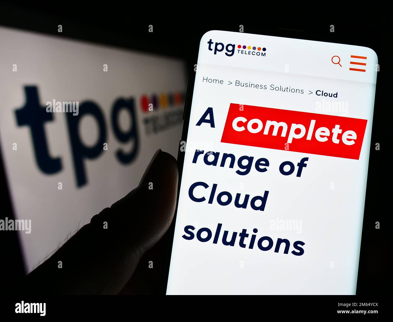 Person holding cellphone with webpage of Australian company TPG Telecom ...