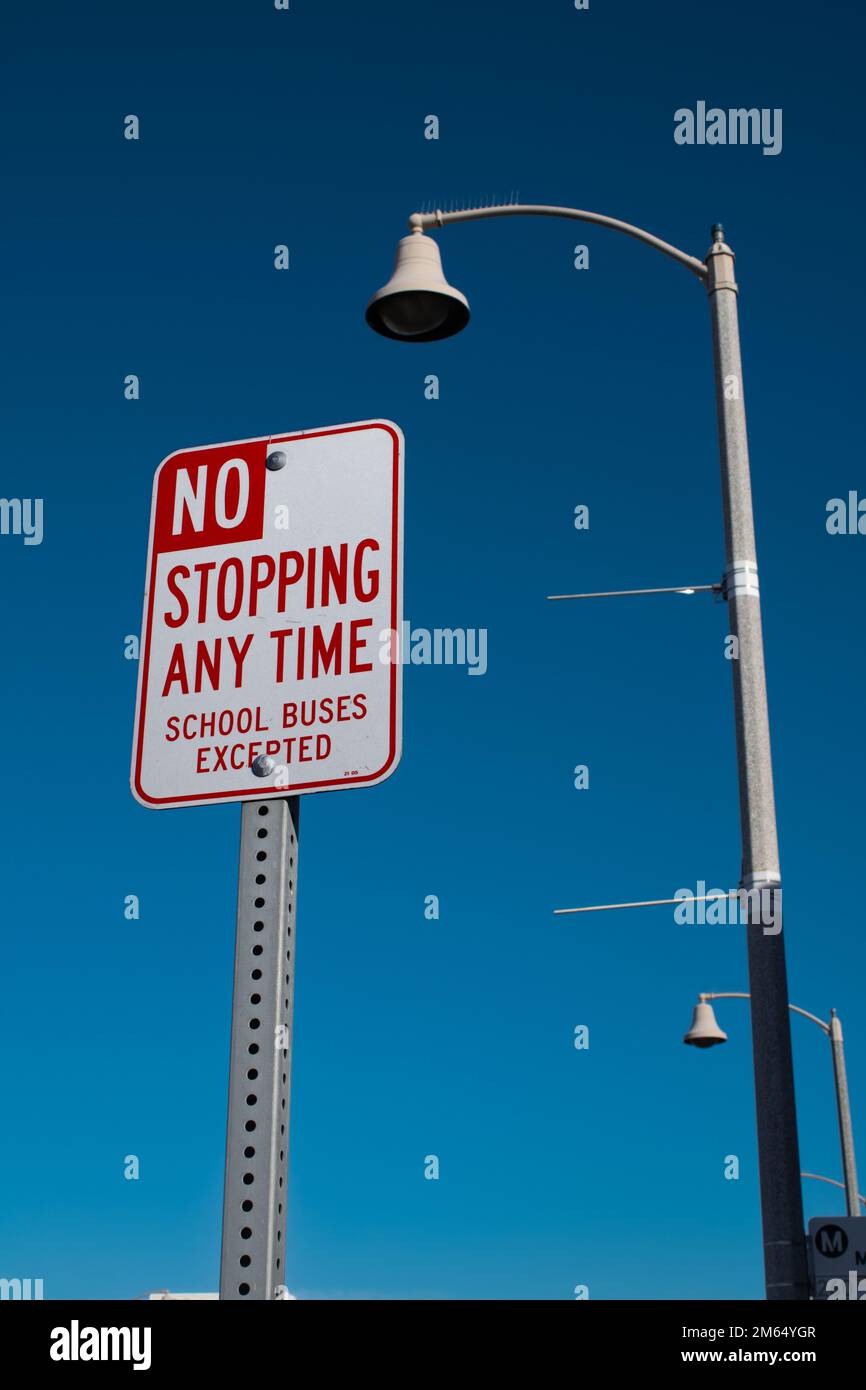 A red sign forbidding all vehicles except school buses to stop with a ...