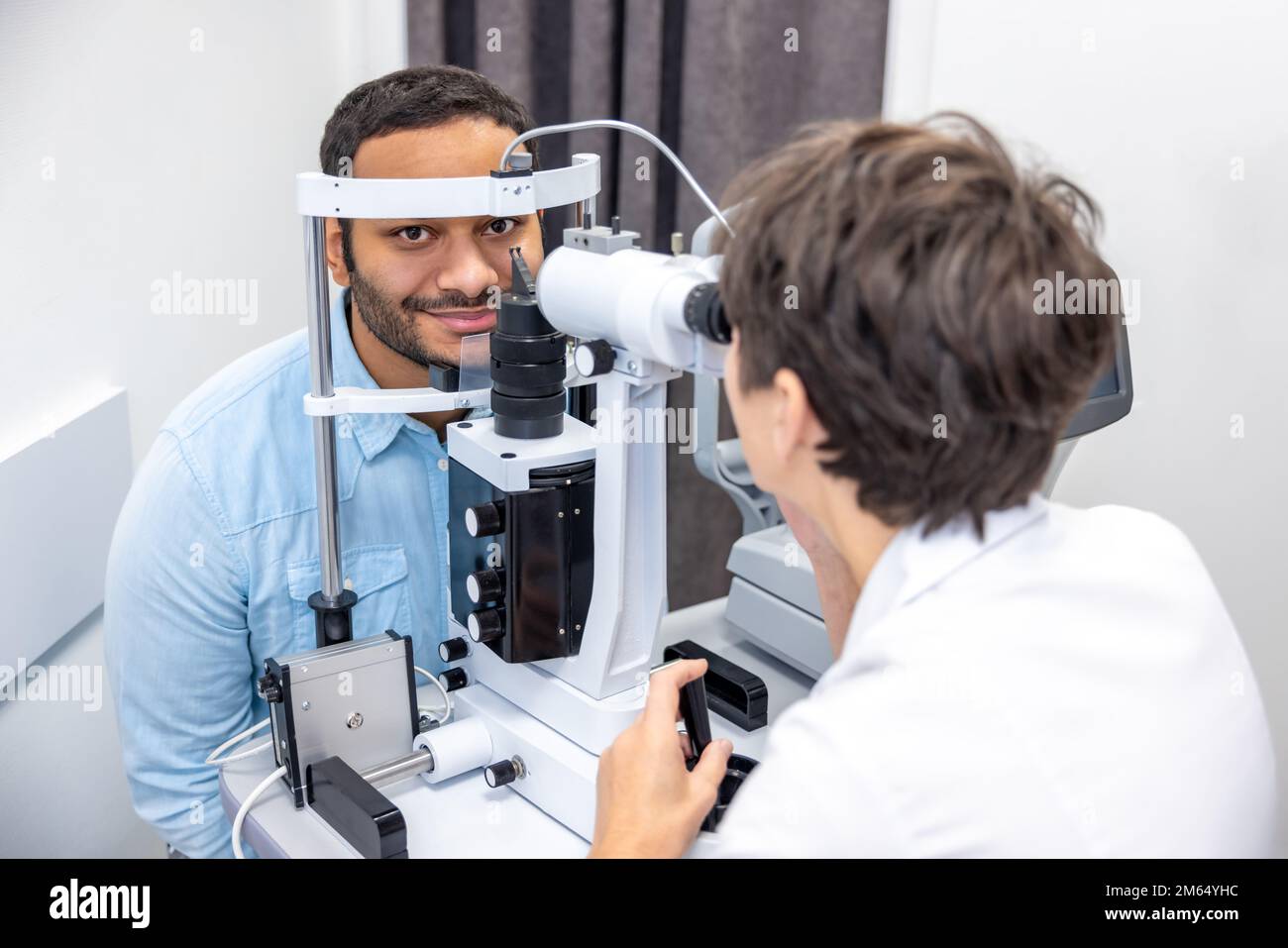 Female doctor examining patients eyes on the optometric equipment Stock ...