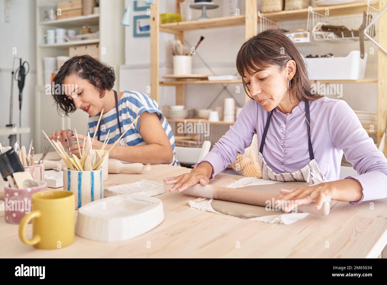 Two women working with clay in a pottery workshop. Craft, art and ...