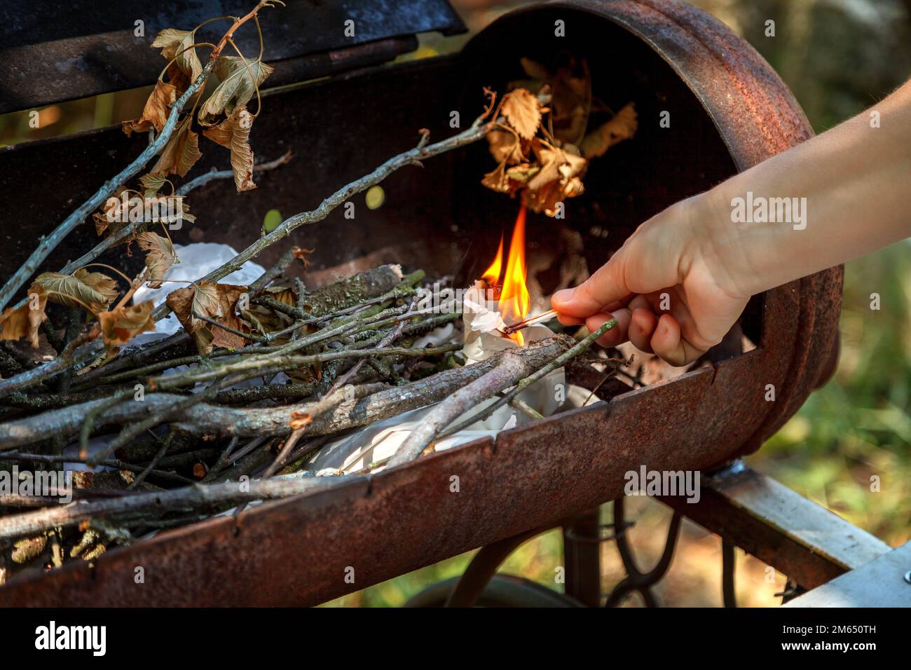Preparing a barbecue for cooking in nature. Kindling with matches paper ...
