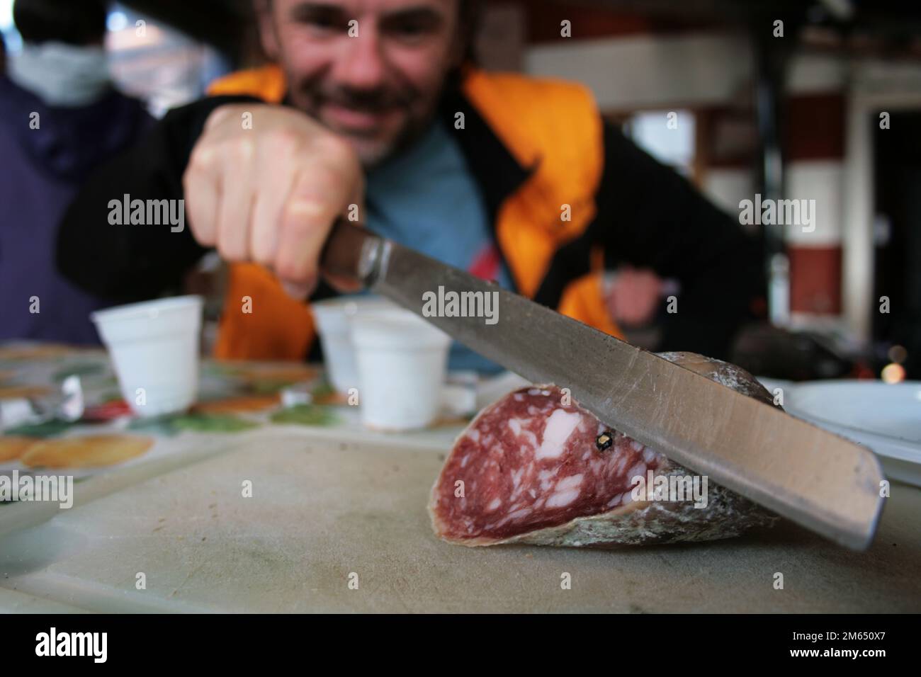 man cutting a slice of salami Stock Photo - Alamy