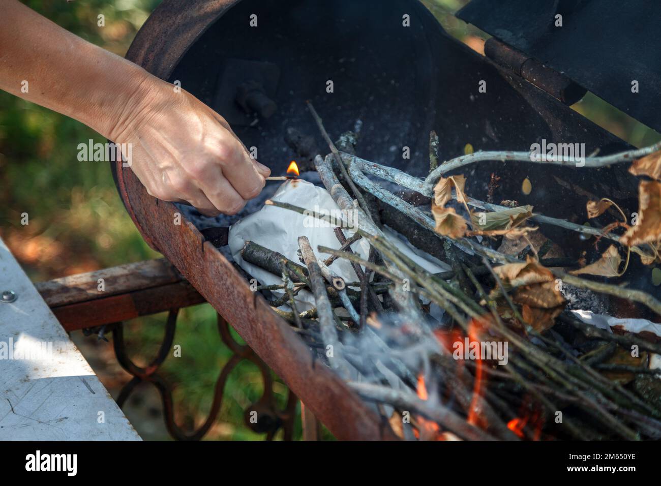 Preparing a barbecue for cooking in nature. Kindling with matches paper ...