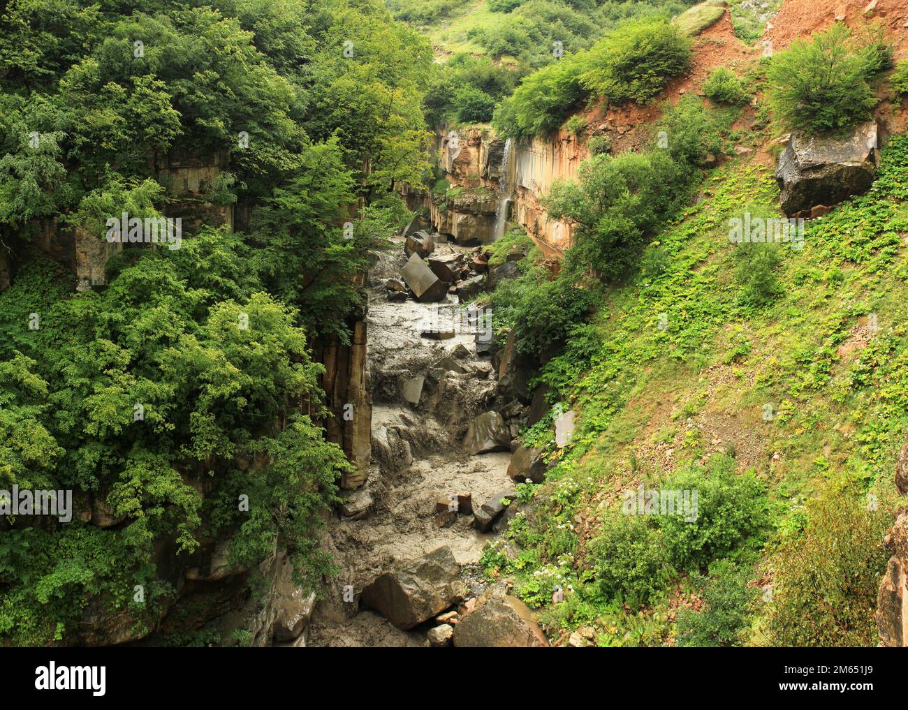 Beautiful waterfall with red mountains in the gorge. The road to the ...