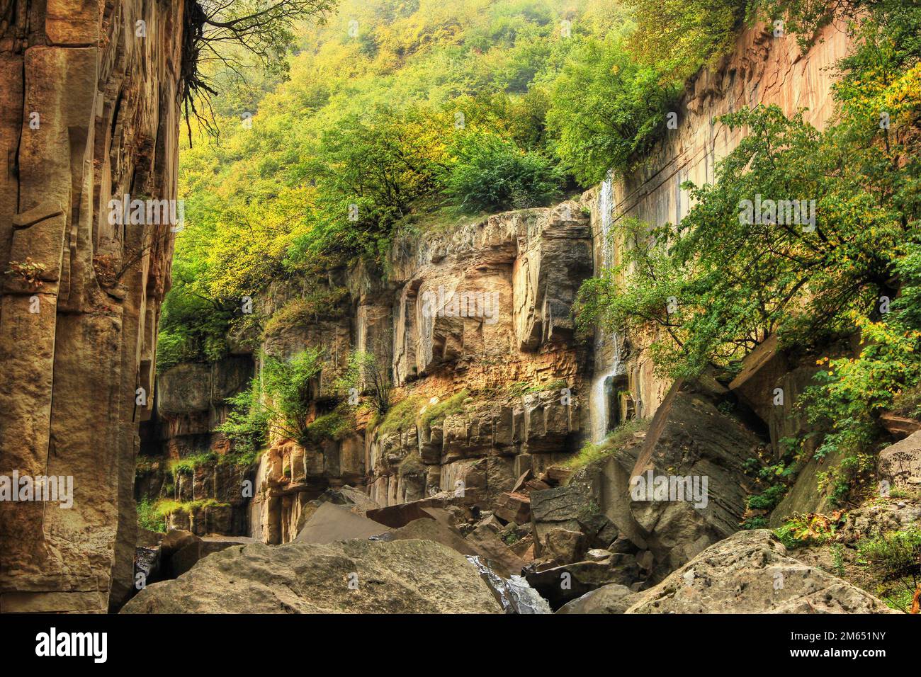 Beautiful waterfall with red mountains in the gorge. The road to the ...