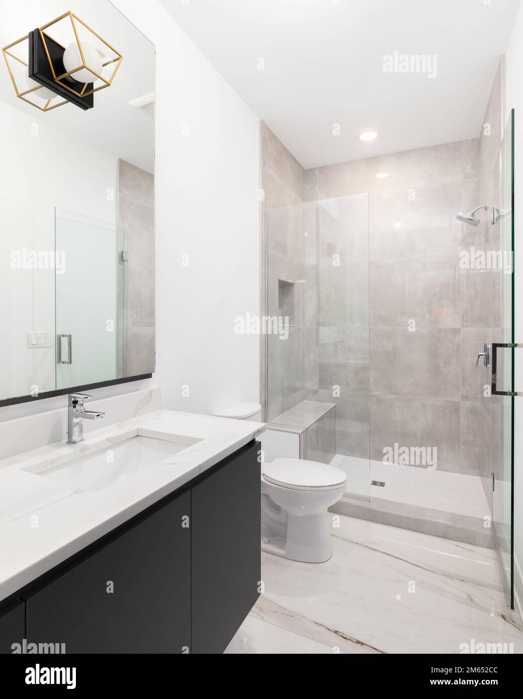 A bathroom with a dark grey floating cabinet, white marble countertop ...