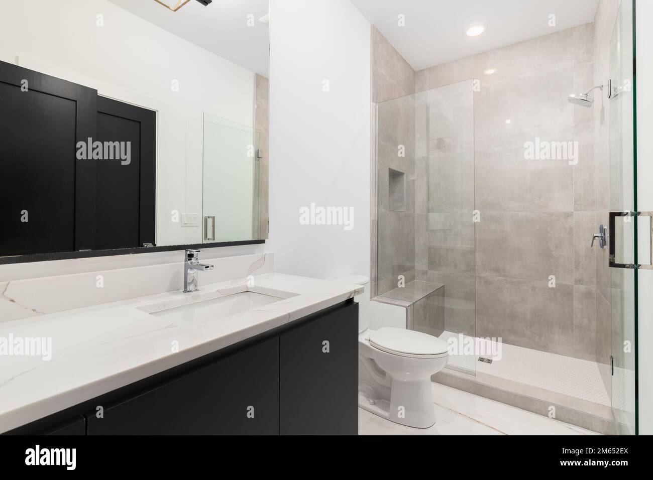 A bathroom with a dark grey floating cabinet, white marble countertop ...