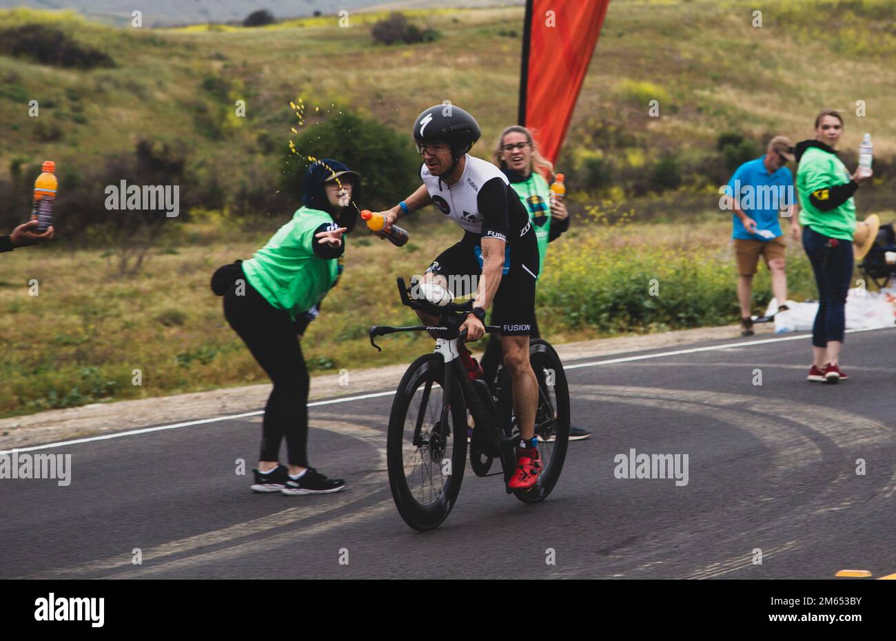 A participant in the Oceanside Ironman 70.3 grabs a bottle from a ...