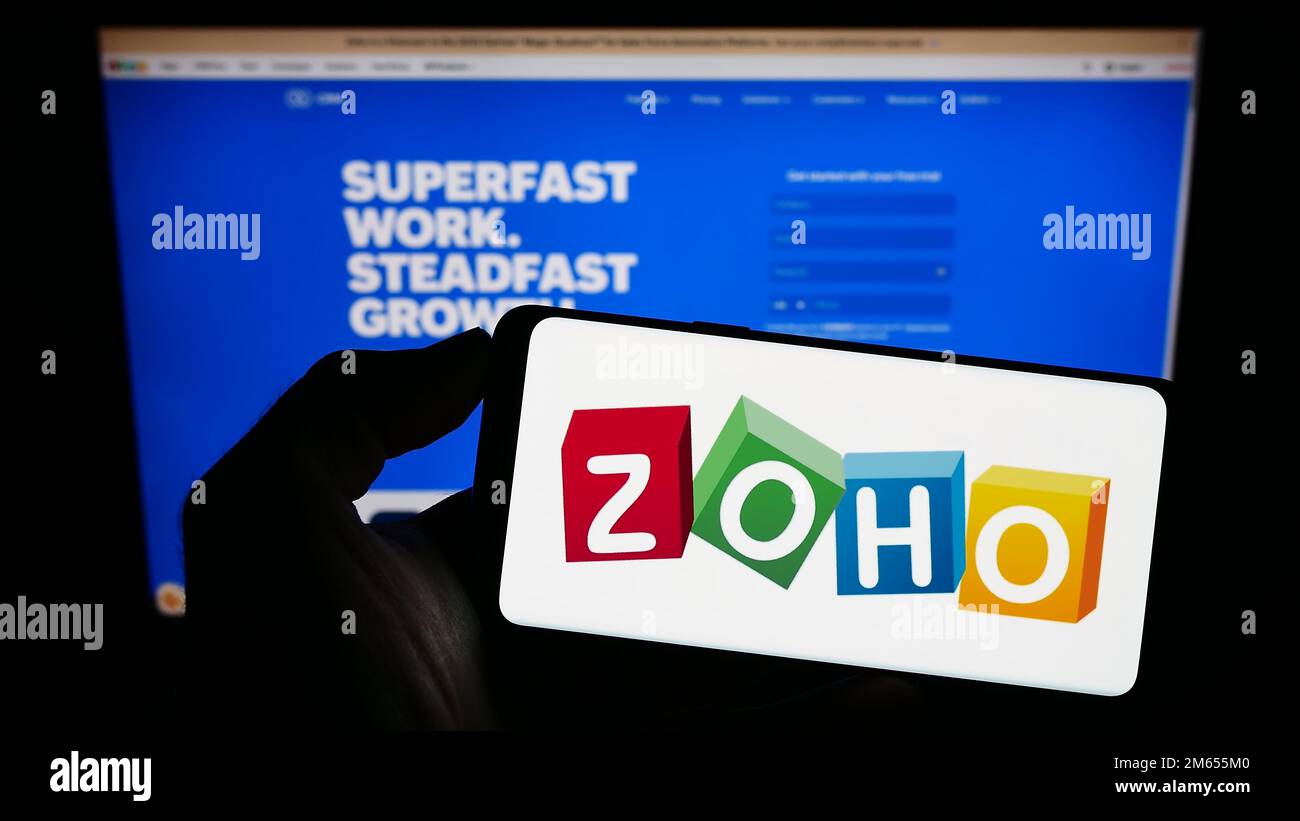 Person holding cellphone with logo of Indian software company Zoho ...