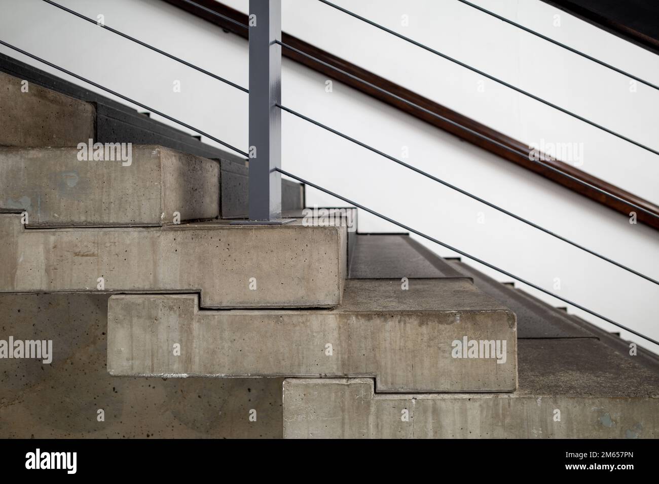 Selective focus at raw concrete riser and tread, and metal railing ...