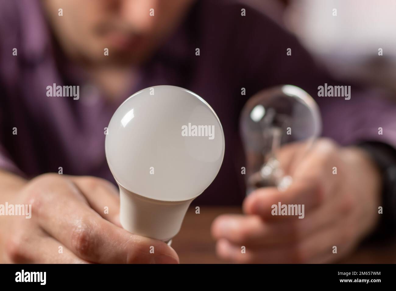 Two lamps in the hands of a man. Incandescent light bulb and LED light ...