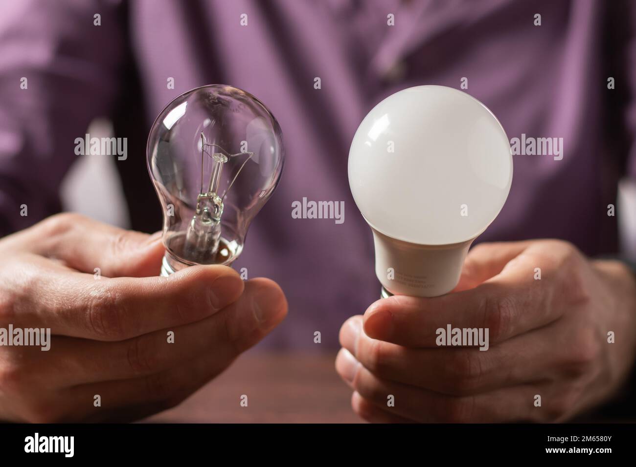Two lamps in the hands of a man. Incandescent light bulb and LED light ...