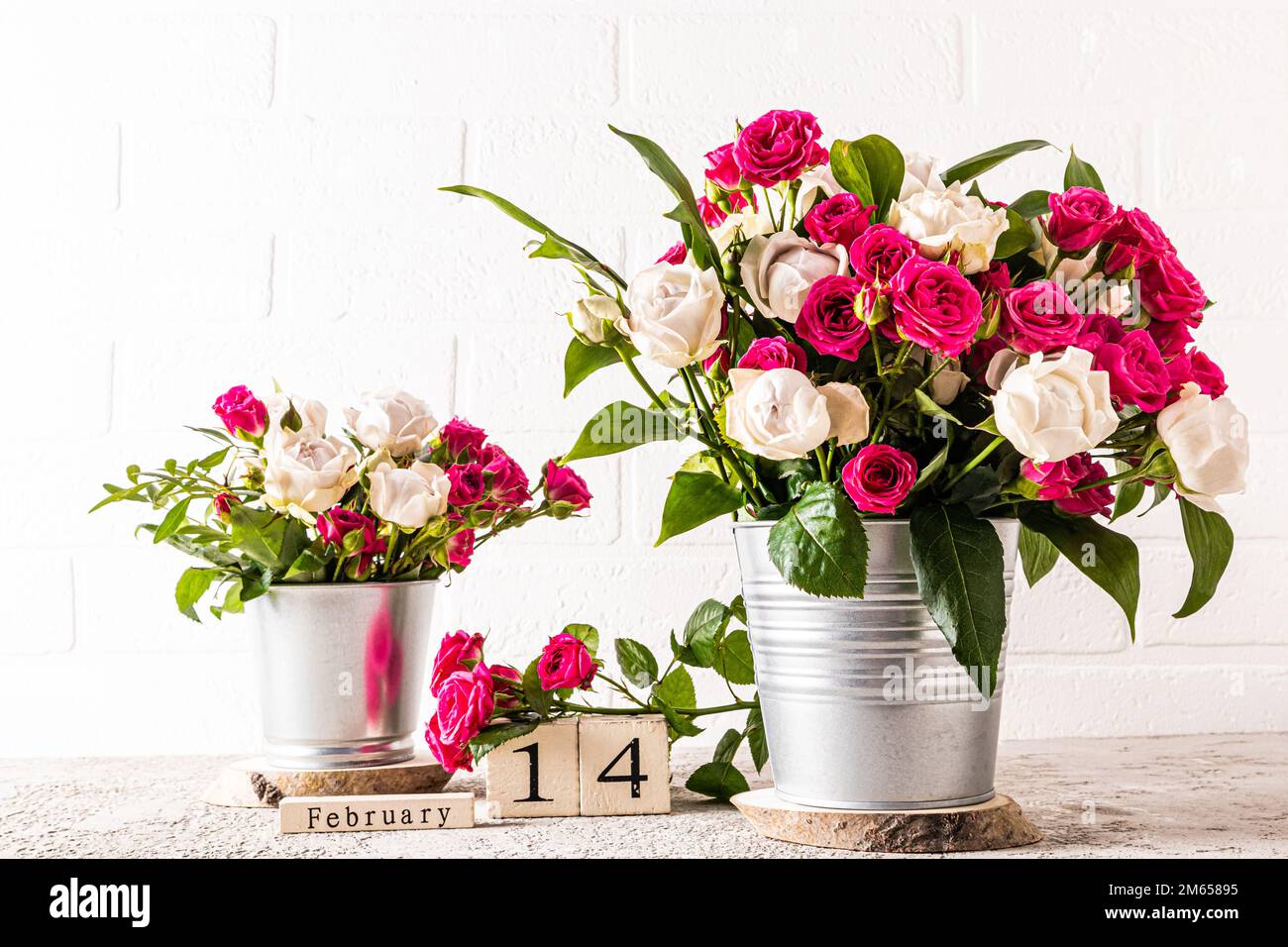 many white and red roses in two metal decorative buckets on a marble ...