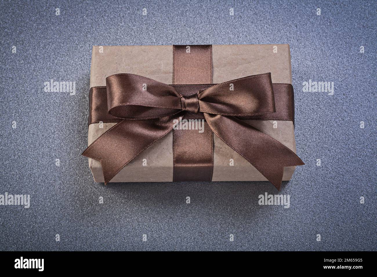 Boxed present in brown shop paper on grey background top view ...