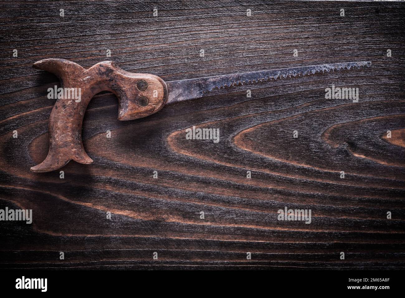 Rusty metal hand saw with sharp blade on vintage dark wooden board top ...