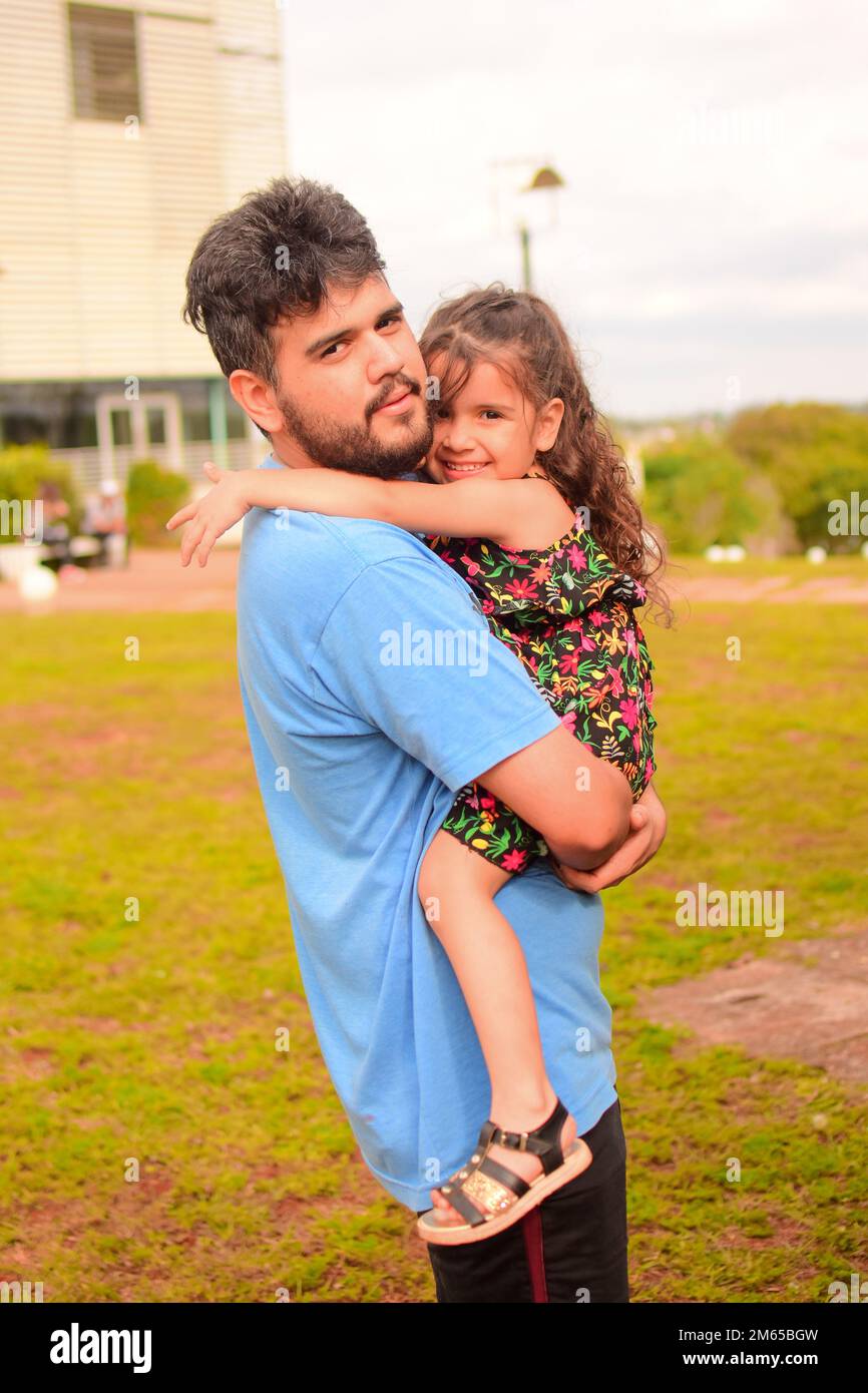 A vertical shot of Hispanic father hugging his daughter on the street ...