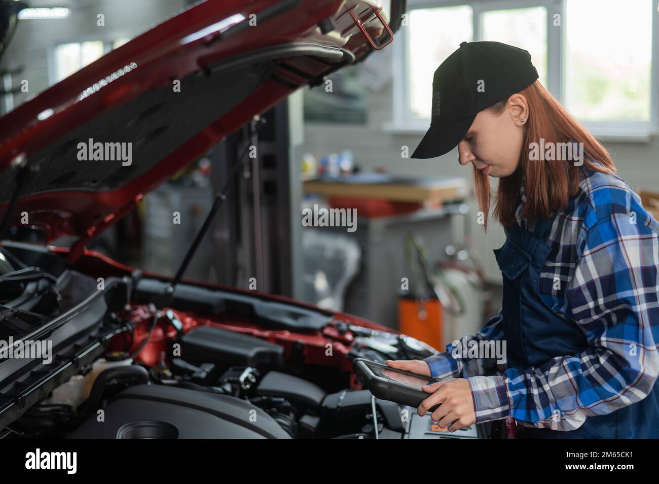 Caucasian female auto mechanic uses a special computer to diagnose ...