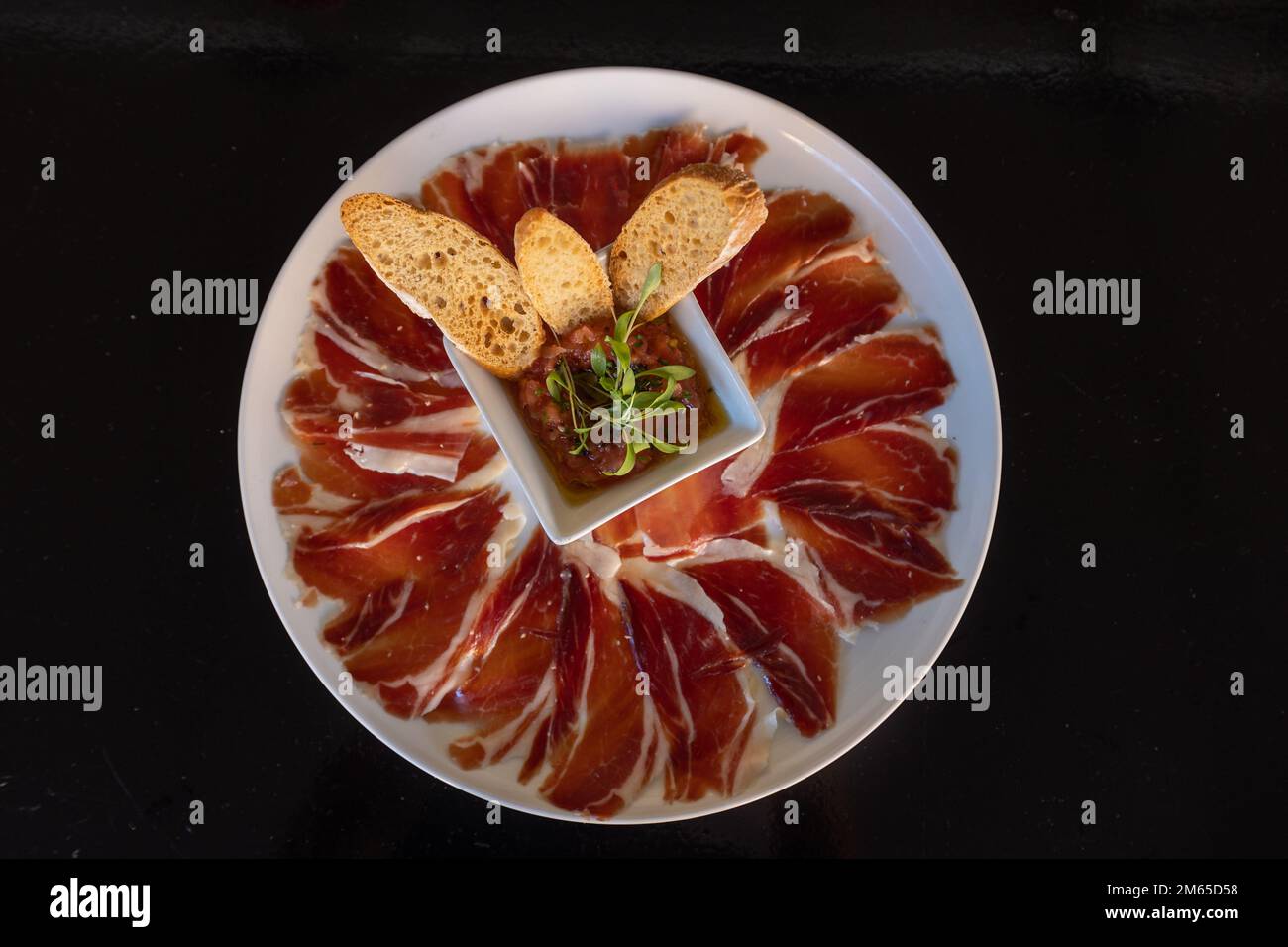 A jamon plate with crosinis on a restaurant table Stock Photo - Alamy