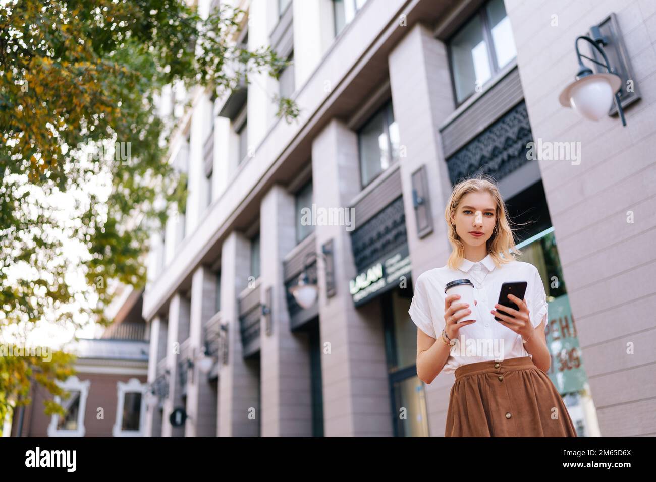 Low-angle view of pretty blonde female teenager in stylish casual ...