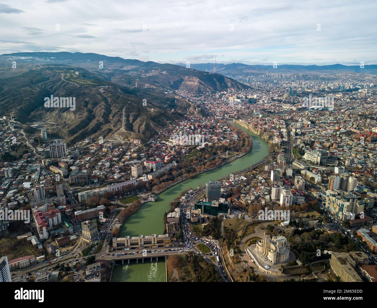An aerial view of Tbilisi cityscape with green mountains with blue ...
