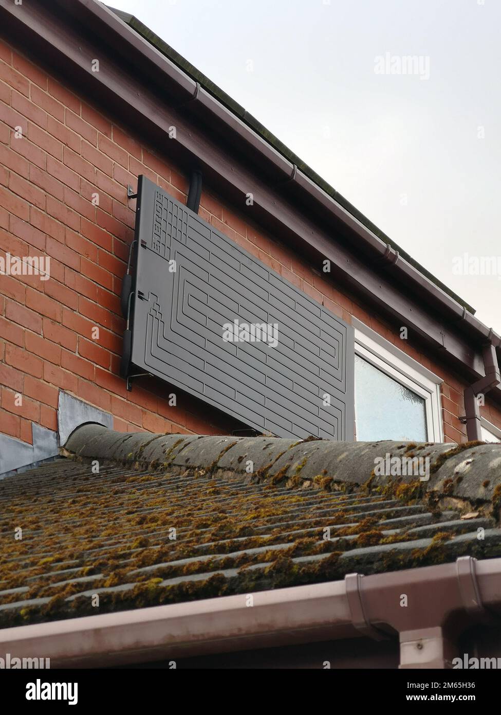 A vertical shot of a solar panel attached to the wall of a building ...