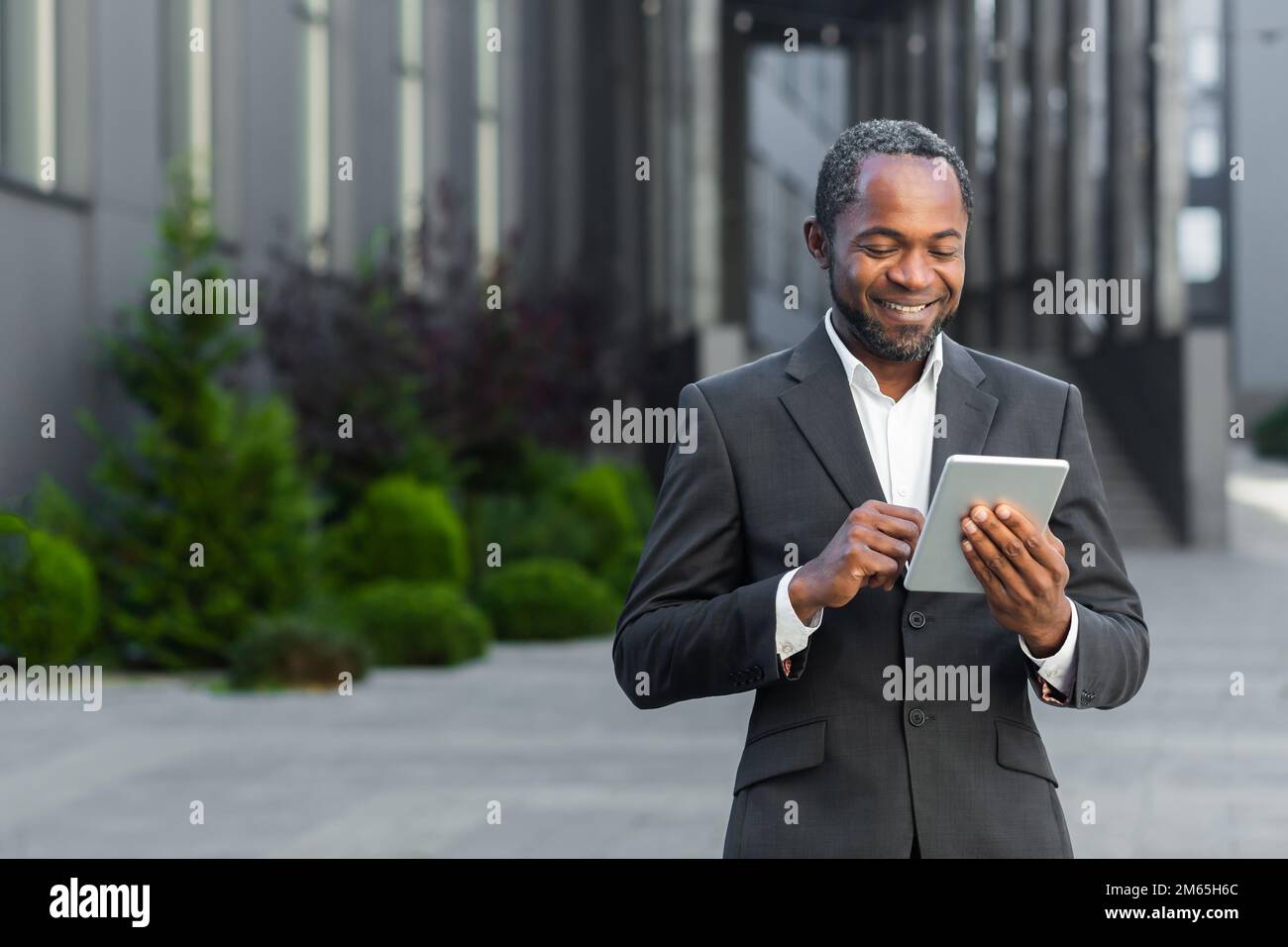 Successful african american man in business suit smiling and using ...