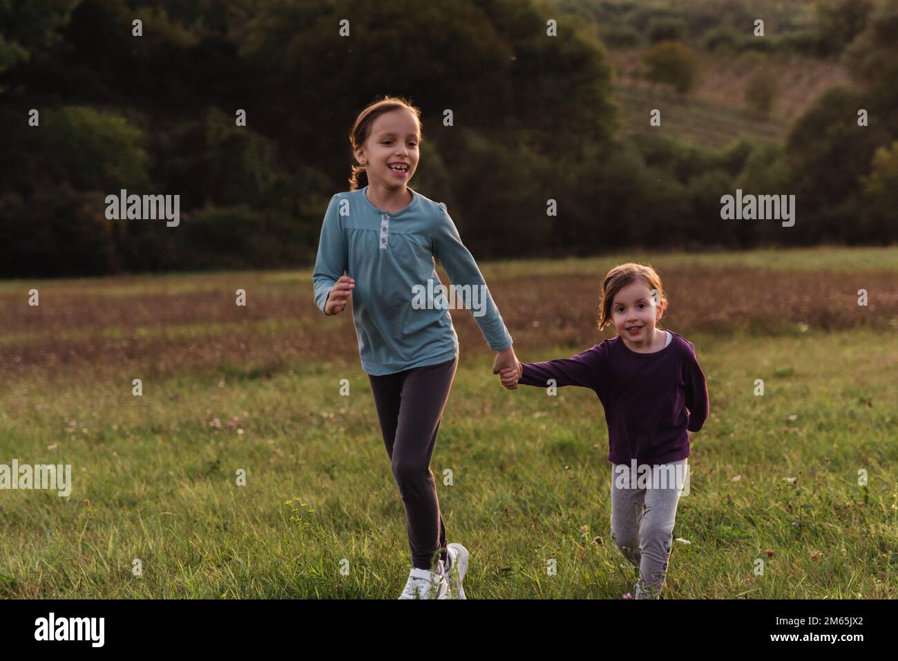 Two girls running holding hands hi-res stock photography and images - Alamy
