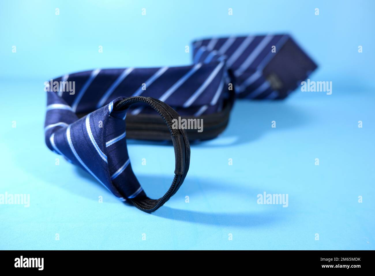 a striped pattern polyester fabric necktie isolated with blue backdrop ...