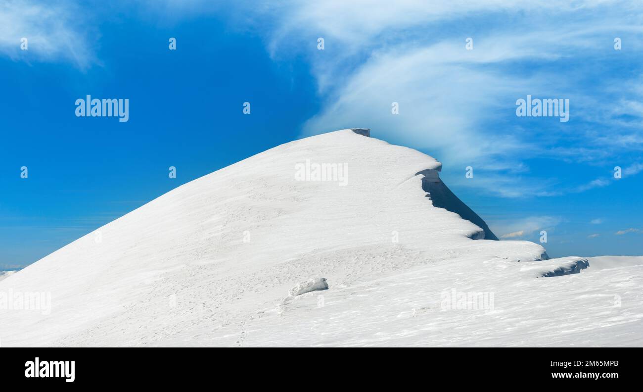 Winter mountains ridge with overhang snow caps and snowboard tracks on ...